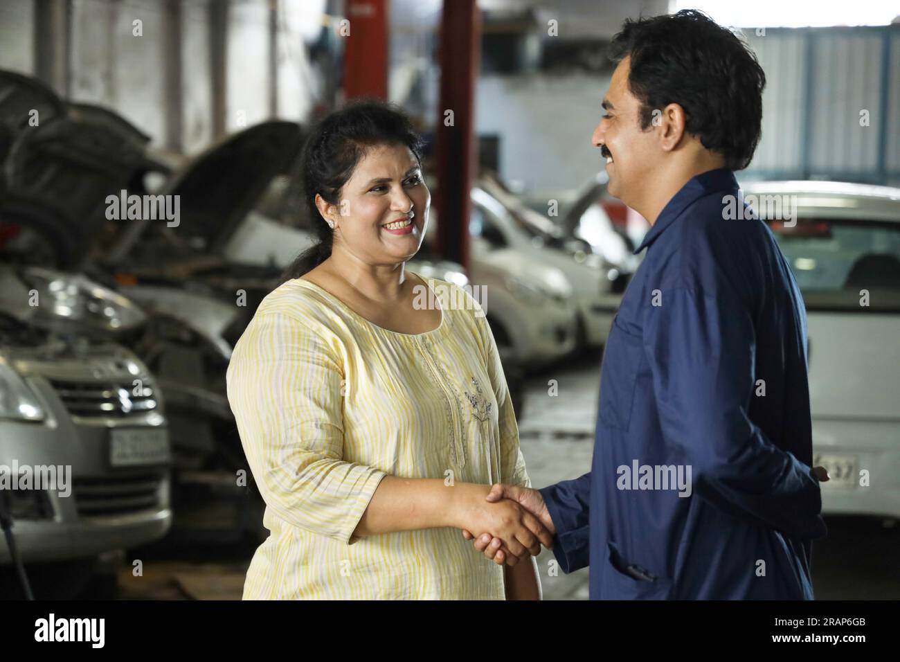 car mechanic standing with the happy customer shaking hands together ...