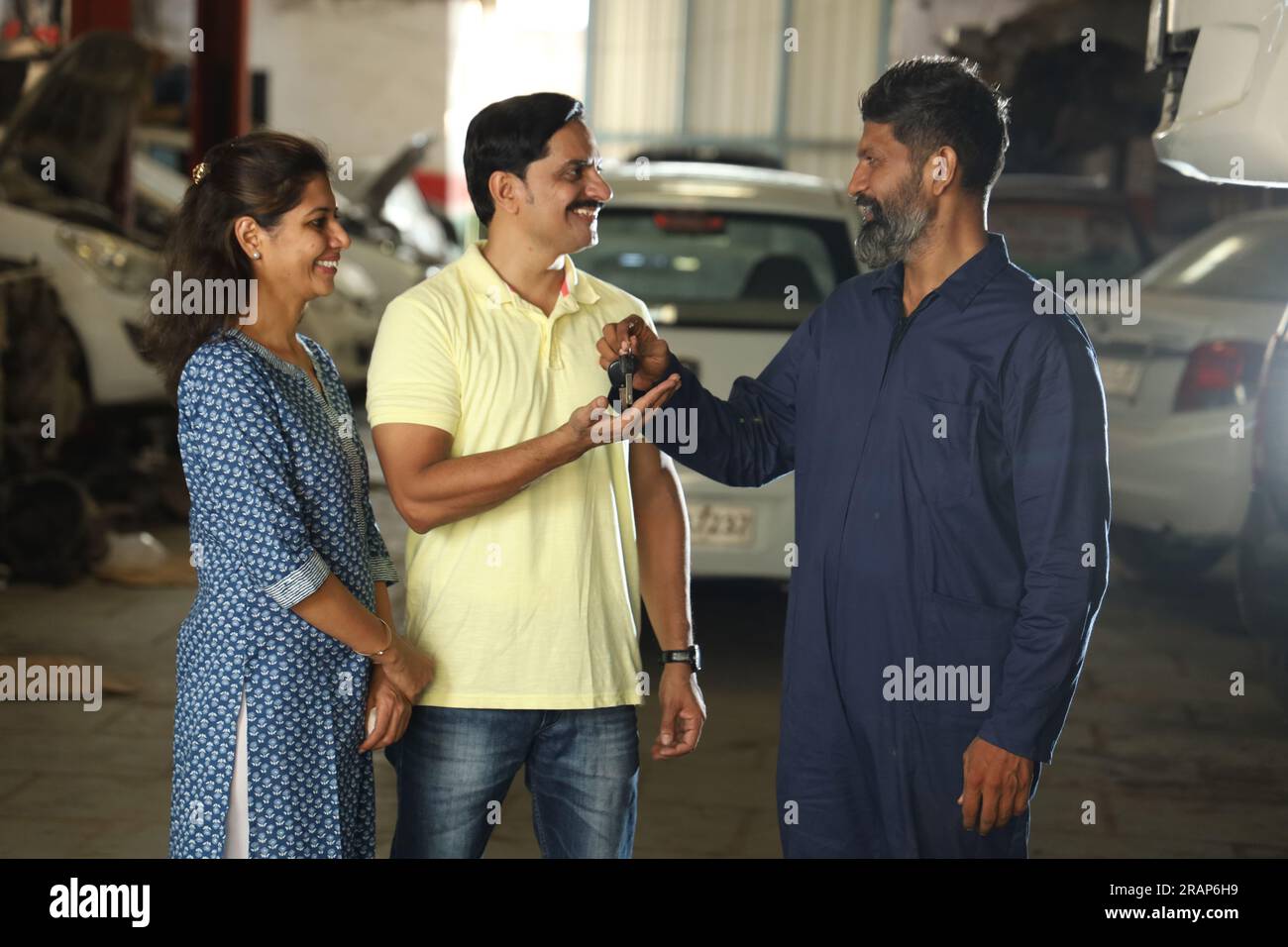 Indian car mechanic delivering the car keys to the happy customers ...