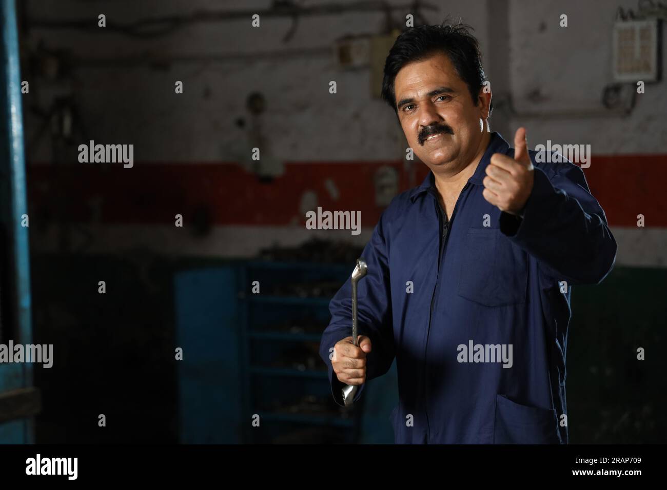 Portrait of a happy car mechanic in moustache standing beside car in ...
