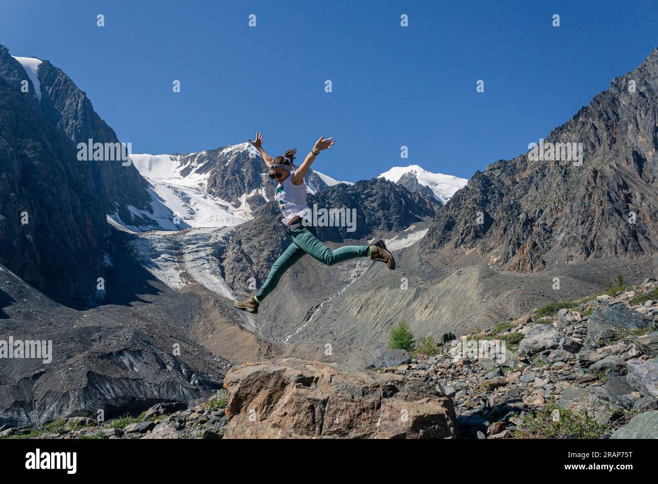 a young woman in a jump against the backdrop of the high mountains of ...