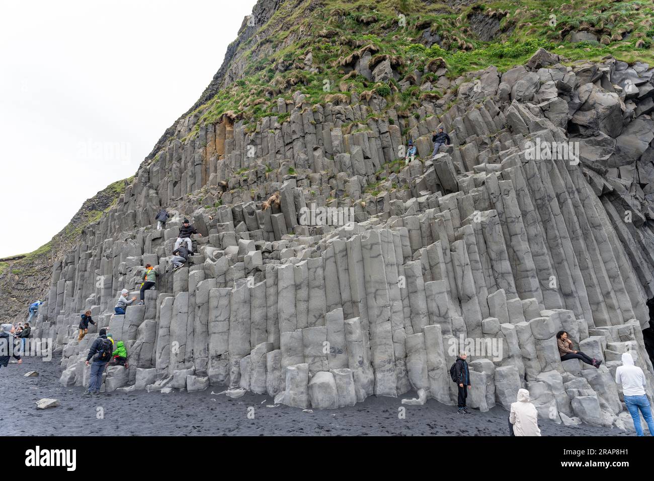 Reynisfjara Black Sand Beach, Iceland - 06.22.2023: People climbing on basalt columns on ...