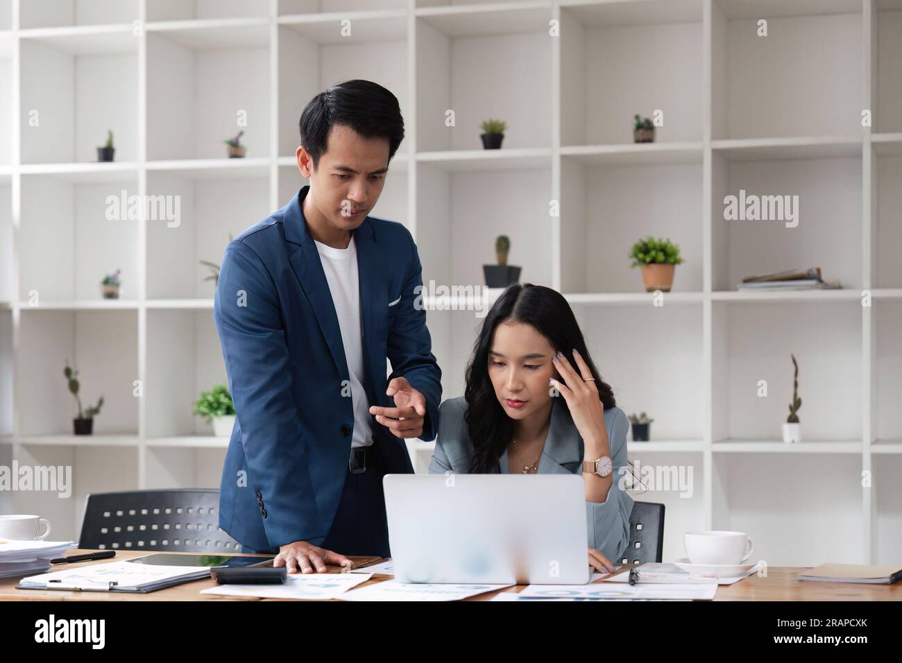 Two business people being stressed while working on a laptop in an ...