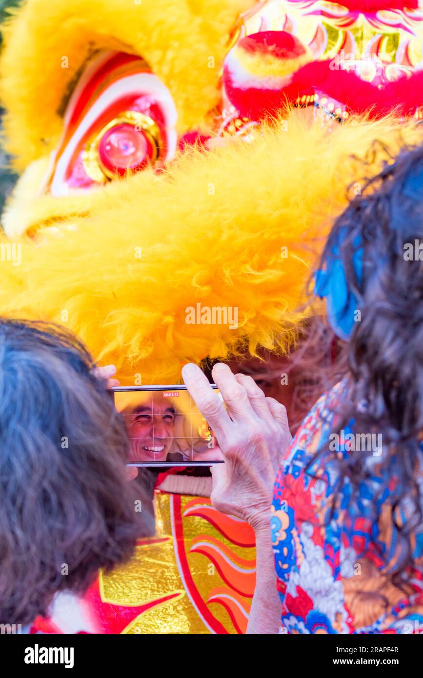A woman captures a smiling face from inside a Chinese Dragon during a ...