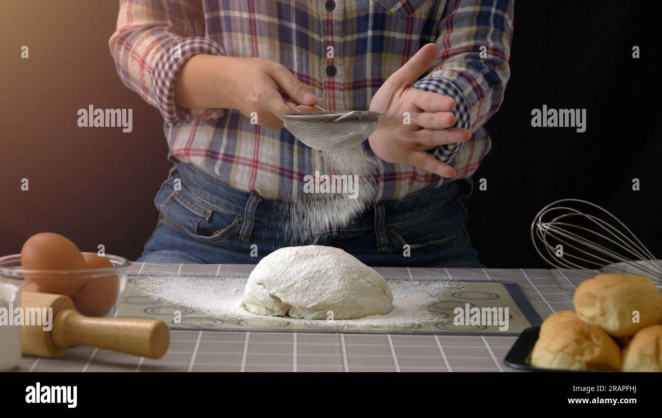artisan bread working with dough. Use a sieve to sift flour into dough ...