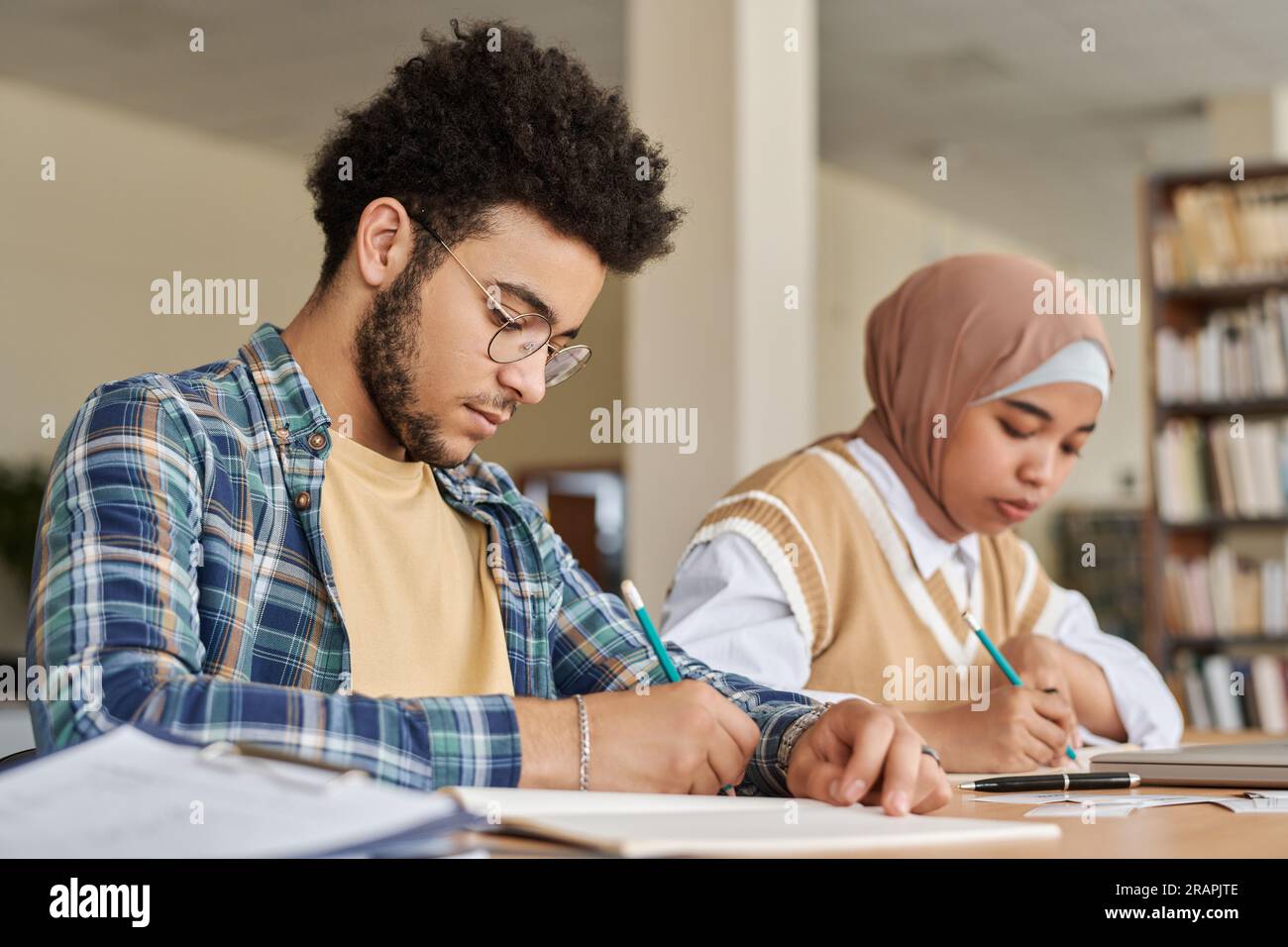 Multiethnic students writing foreign language exam at table in class ...