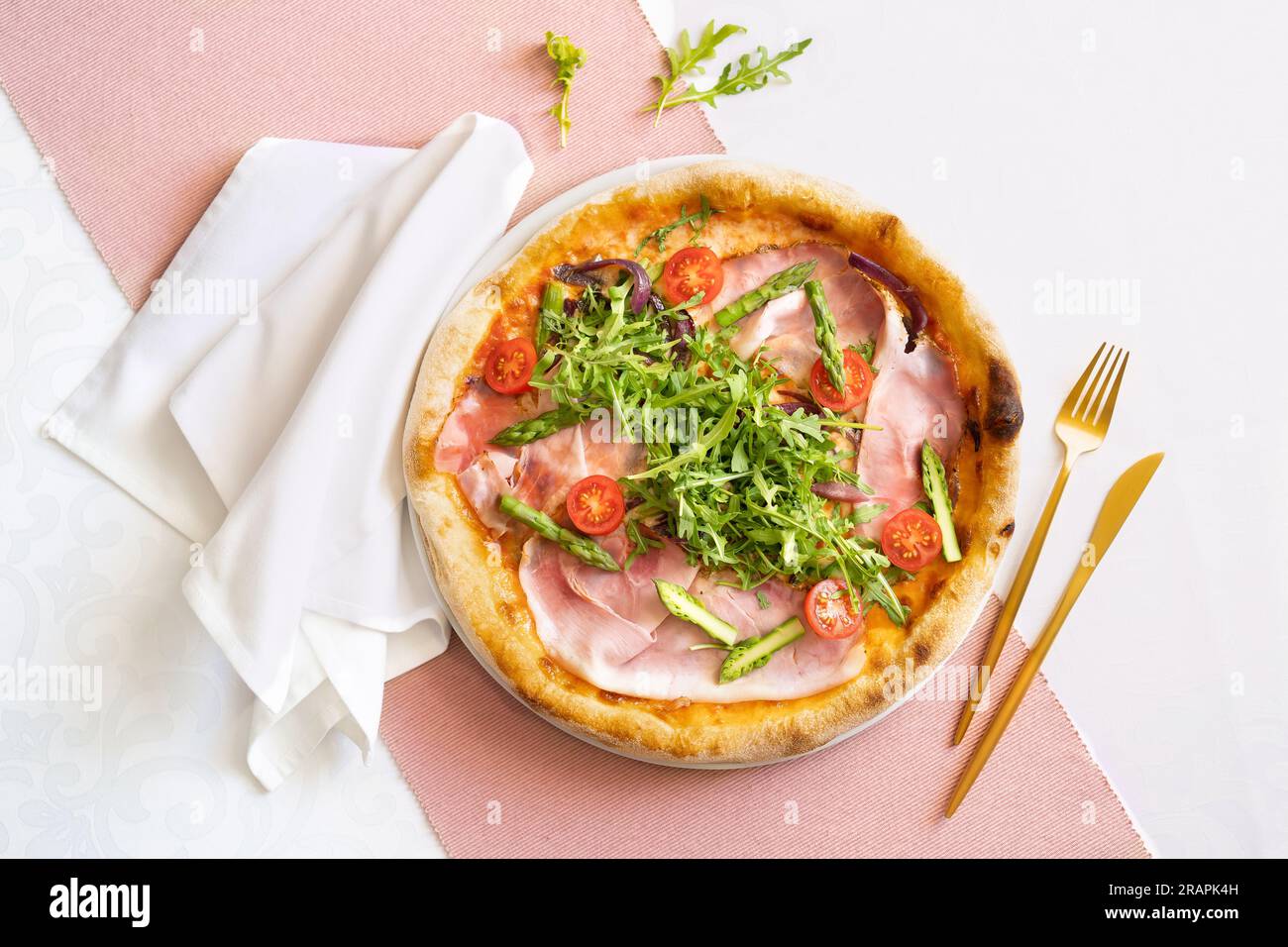 Top view of a ham pizza with ham, asparagus, tomatoes, and arugula ...