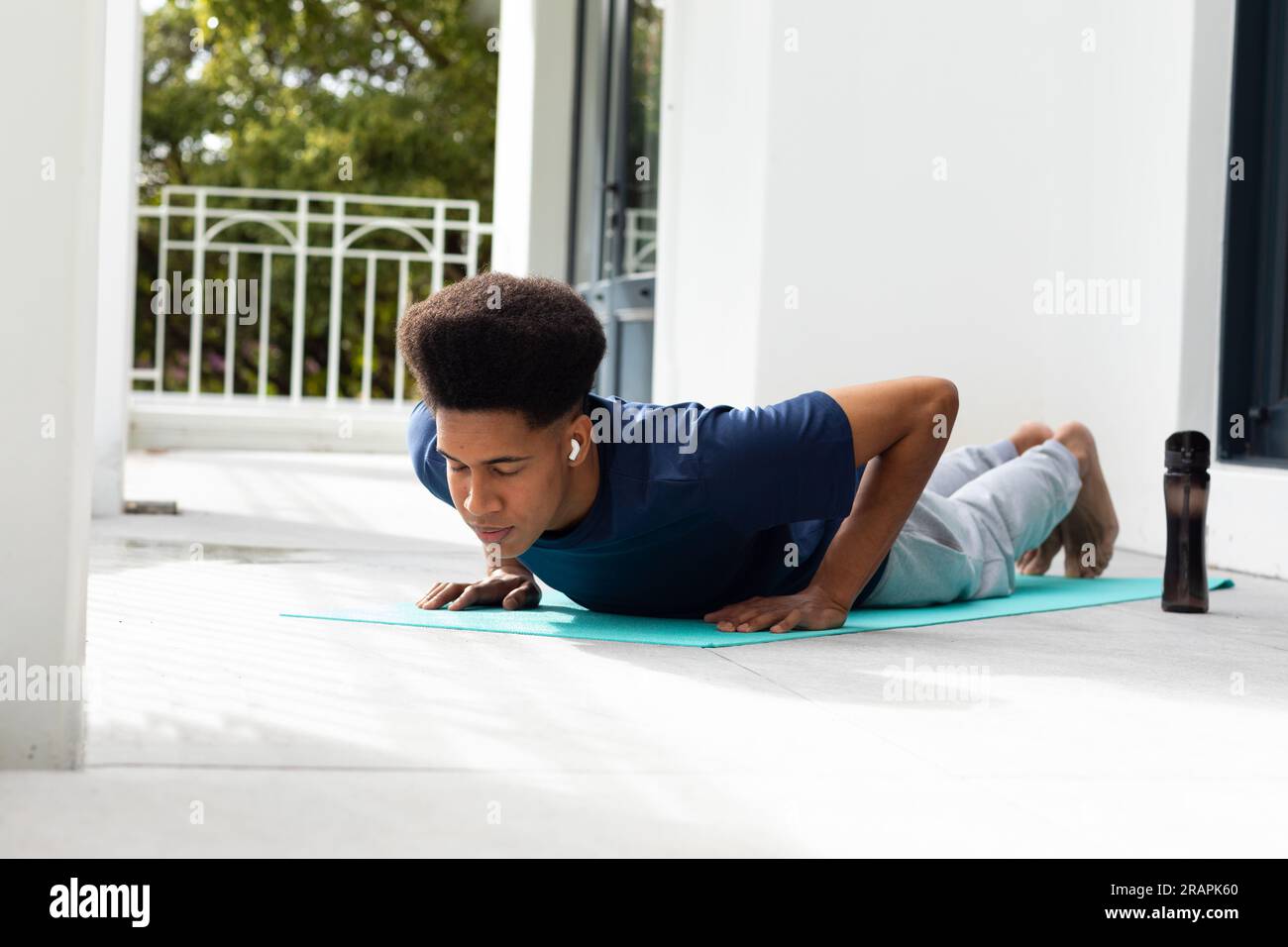 Focused biracial man doing yoga lying on sunny balcony. Cobra pose ...