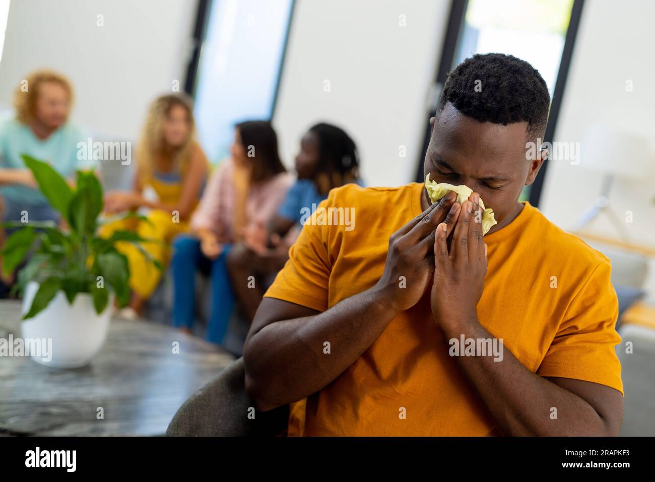 Distressed african american man holding tissue and crying in group ...