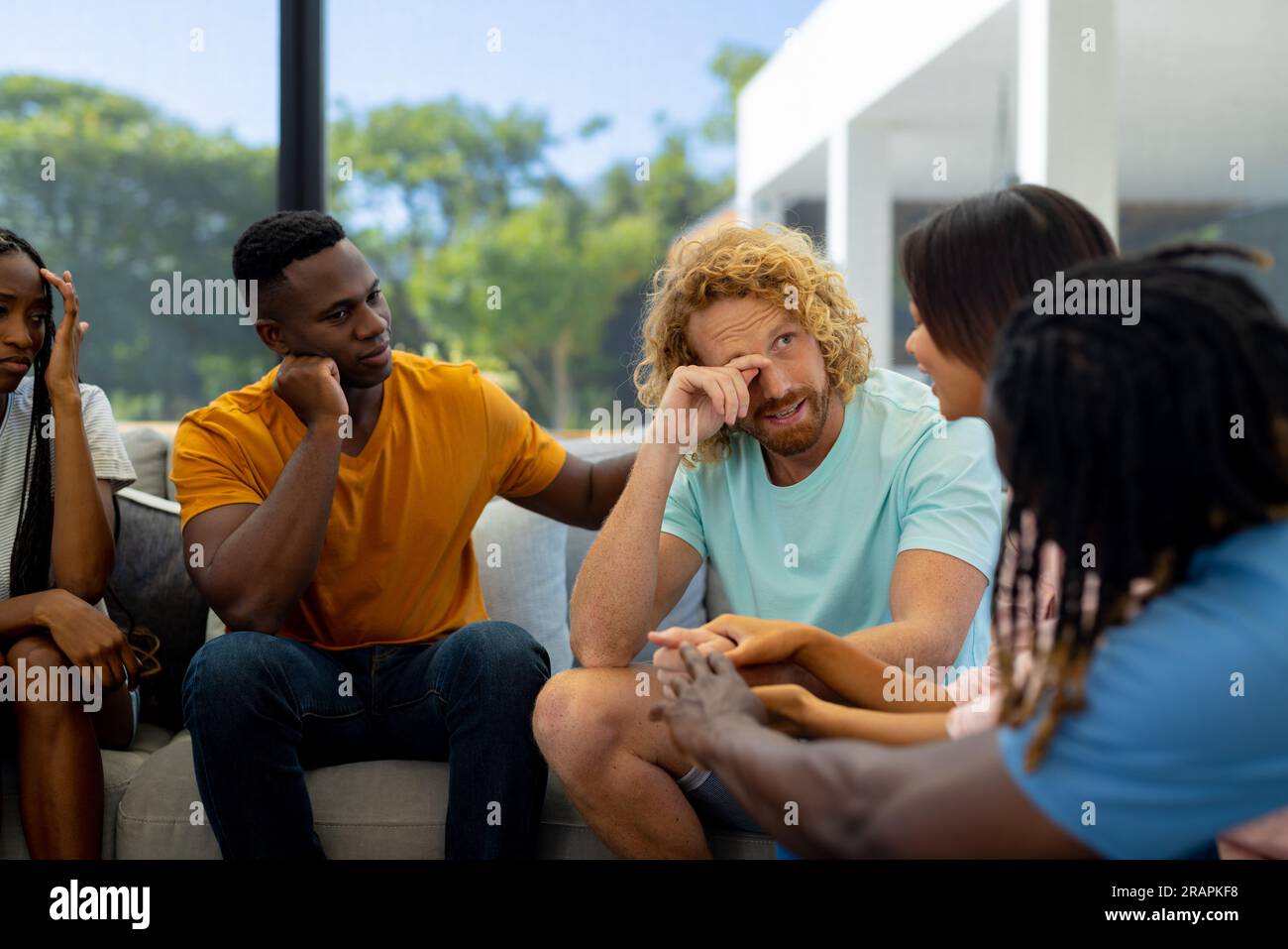 Group of diverse people sitting on sofa and talking in group therapy ...