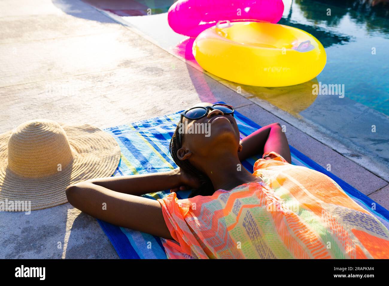 Happy african american woman lying on towel and sunbathing next to ...