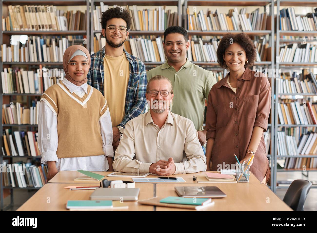 Portrait of migrant students with teacher smiling at camera while ...