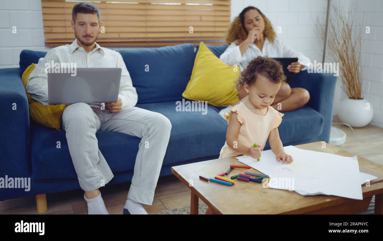 Dad and mom sitting on sofa with computer while daughter painting in ...
