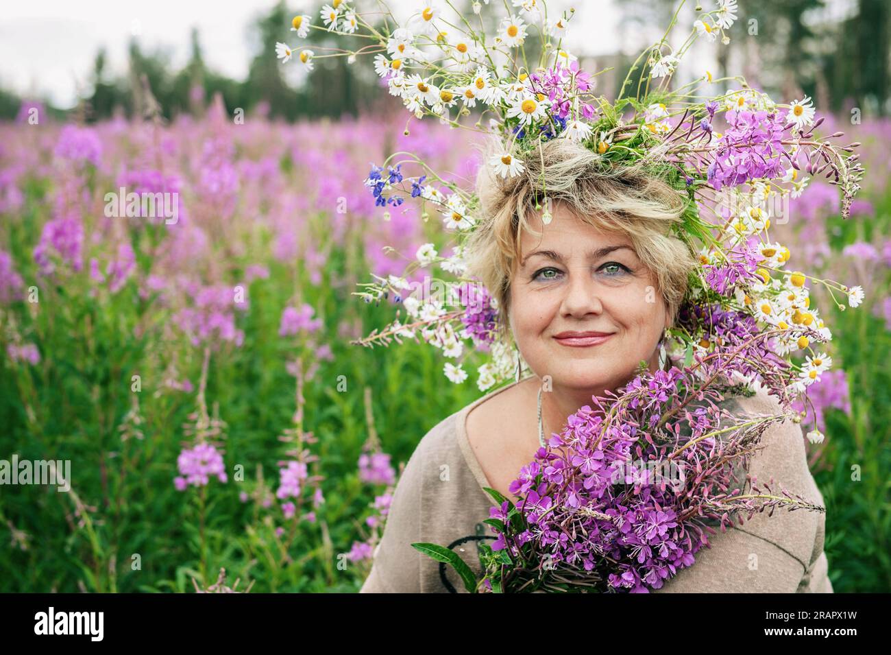 Beautiful 60s mid mature woman at nature in a a wreath of flowers in ...