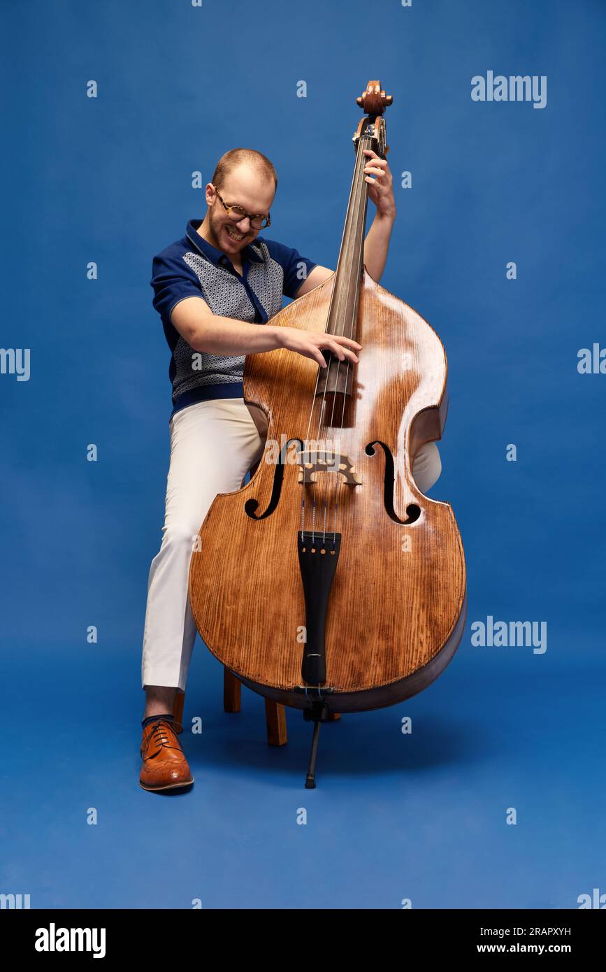 Artistic, emotional man in elegant clothes playing double bass against ...