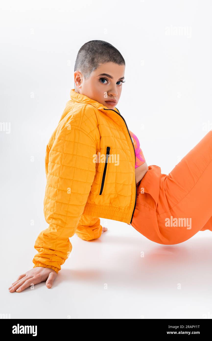 urban fashion, young woman in colorful clothes posing on grey ...