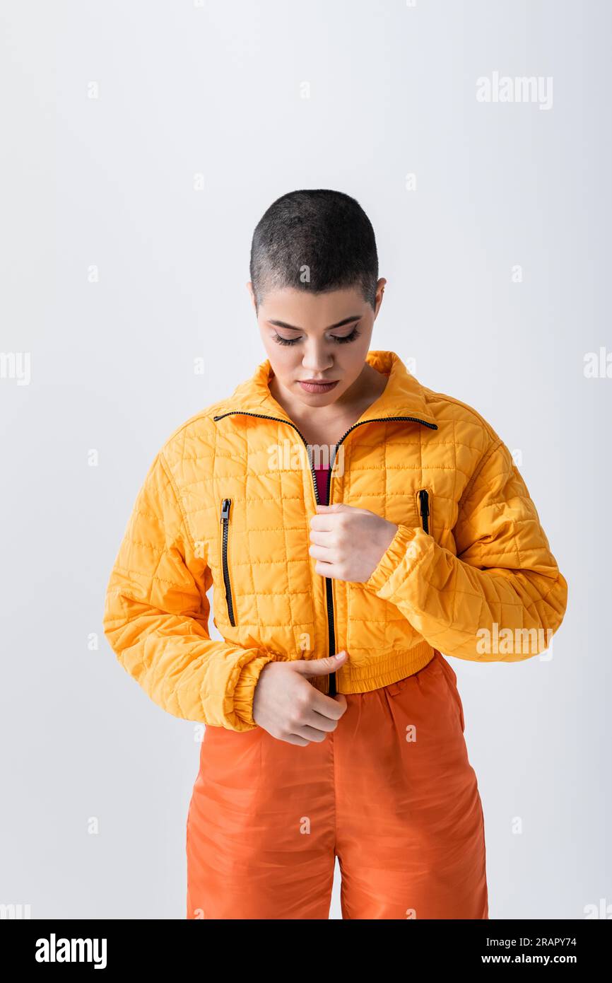 outerwear, young woman with short hair zipping yellow puffer jacket on ...