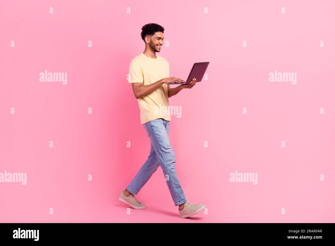 Full length body cadre of walking with netbook young man writing ...