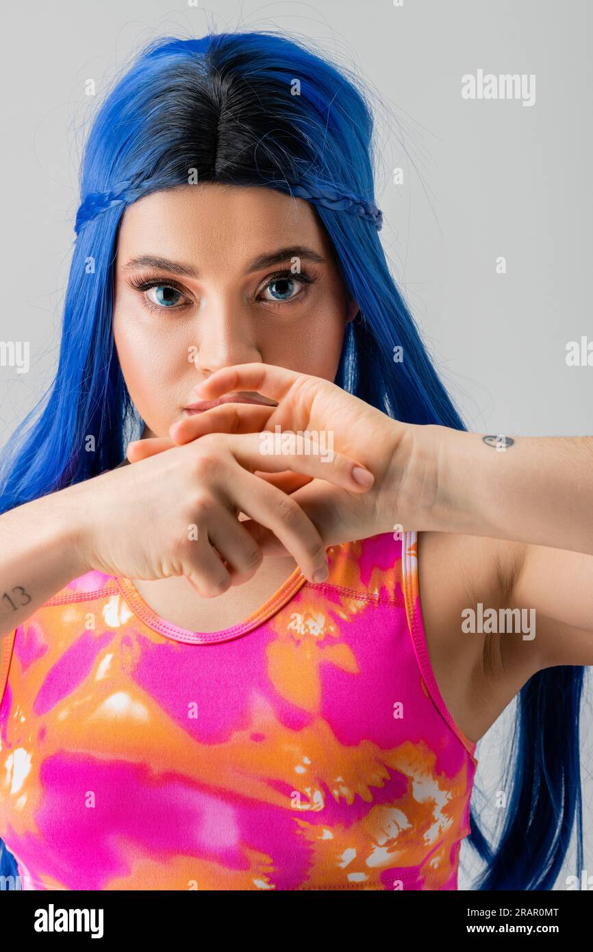 fashion forward, tattooed young woman with blue hair posing with hands ...