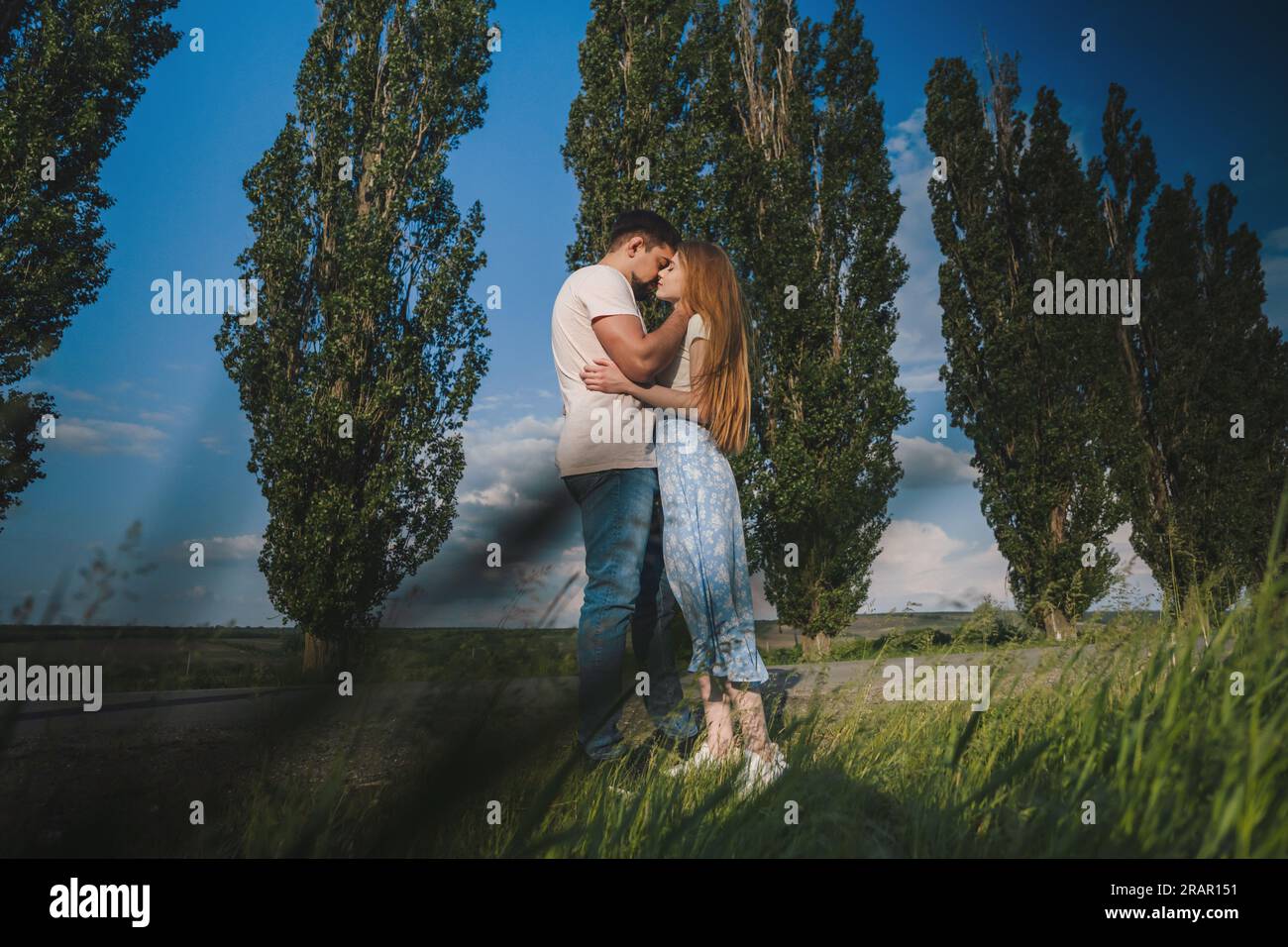 Happy young couple kissing on a green meadow. Full length. Beautiful ...