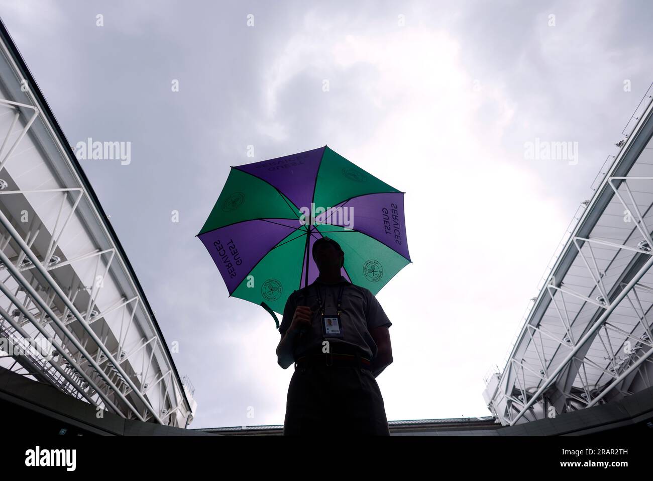 A member of the armed forces on centre court shelters from the rain ...