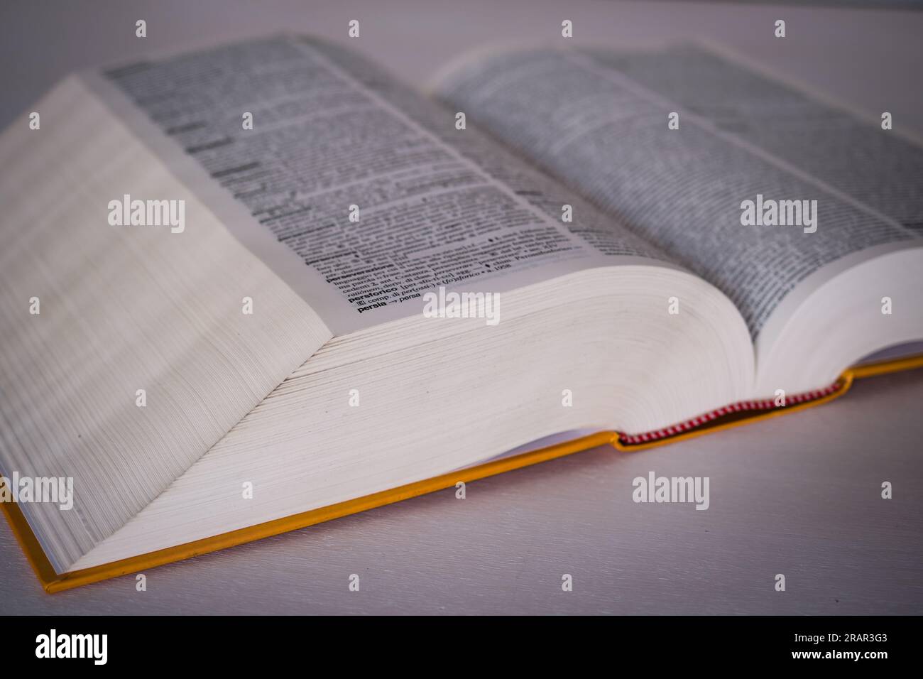 Old open dictionary framed laterally which highlights the thousands of ...