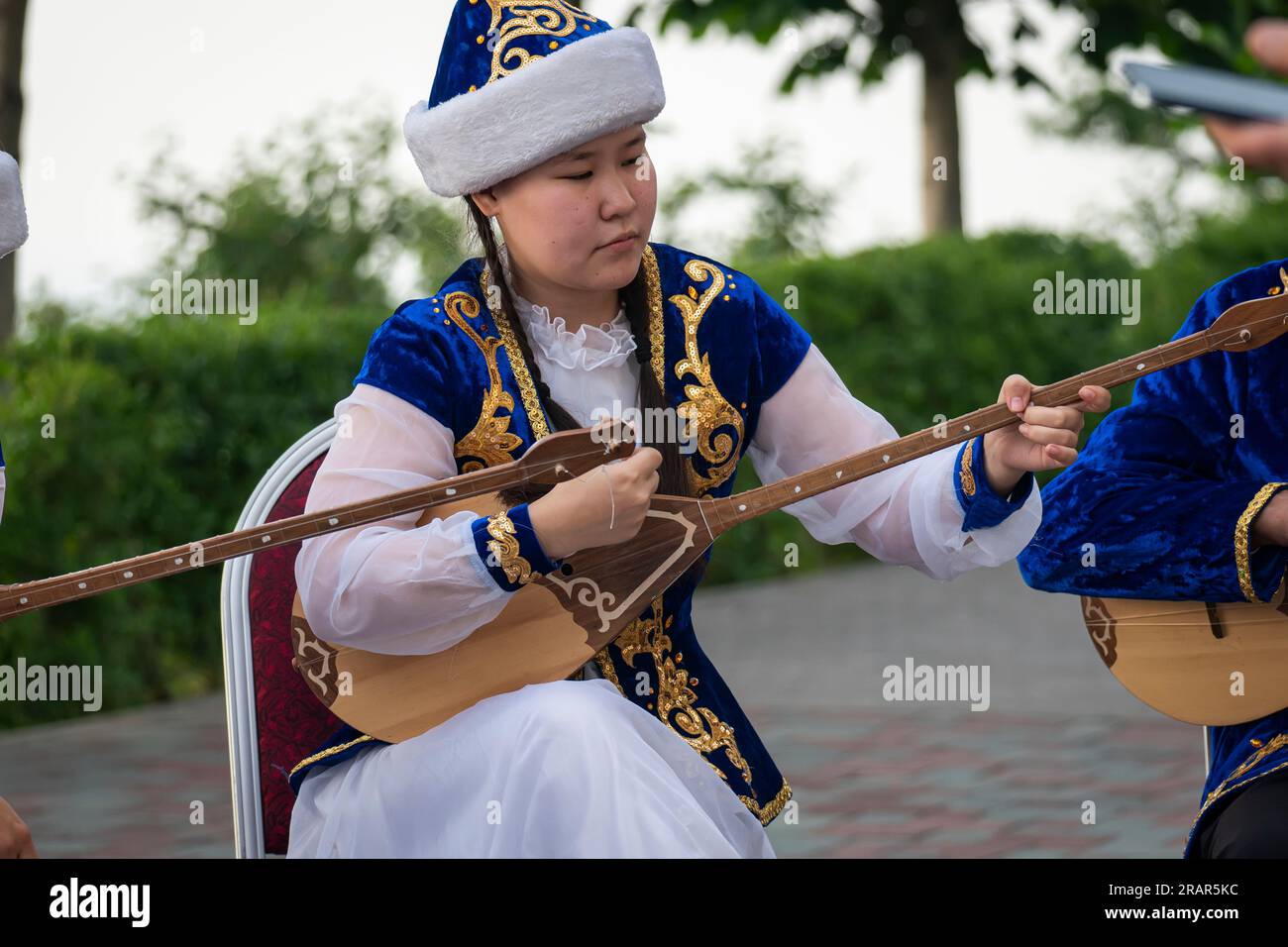 Kazakh woman in blue costume playing dombra Kazakh musical instrument ...