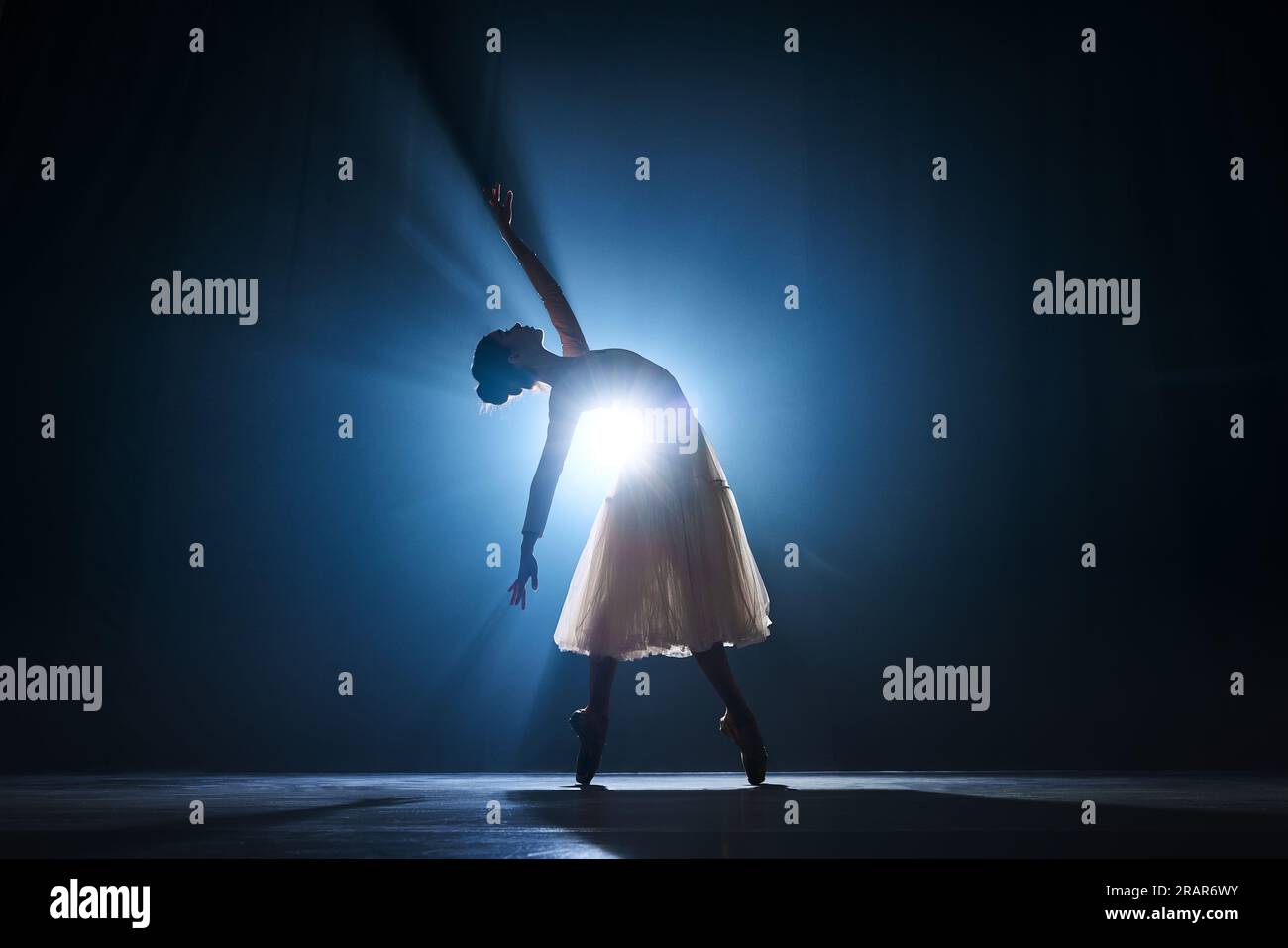 Silhouette of tender, graceful young woman, ballerina performing, dancing over dark blue ...