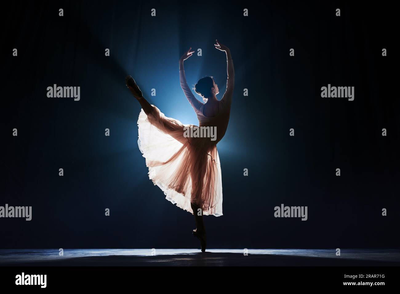 Silhouette of tender, graceful young woman, ballerina performing, dancing over dark blue ...