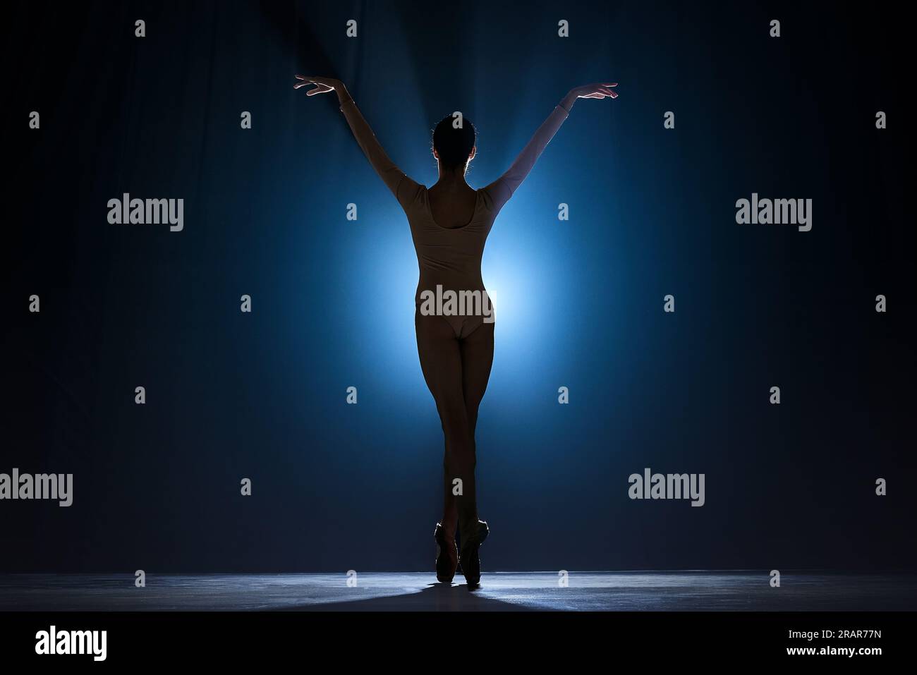 Silhouette of tender, graceful young woman, ballerina performing, dancing over dark blue ...