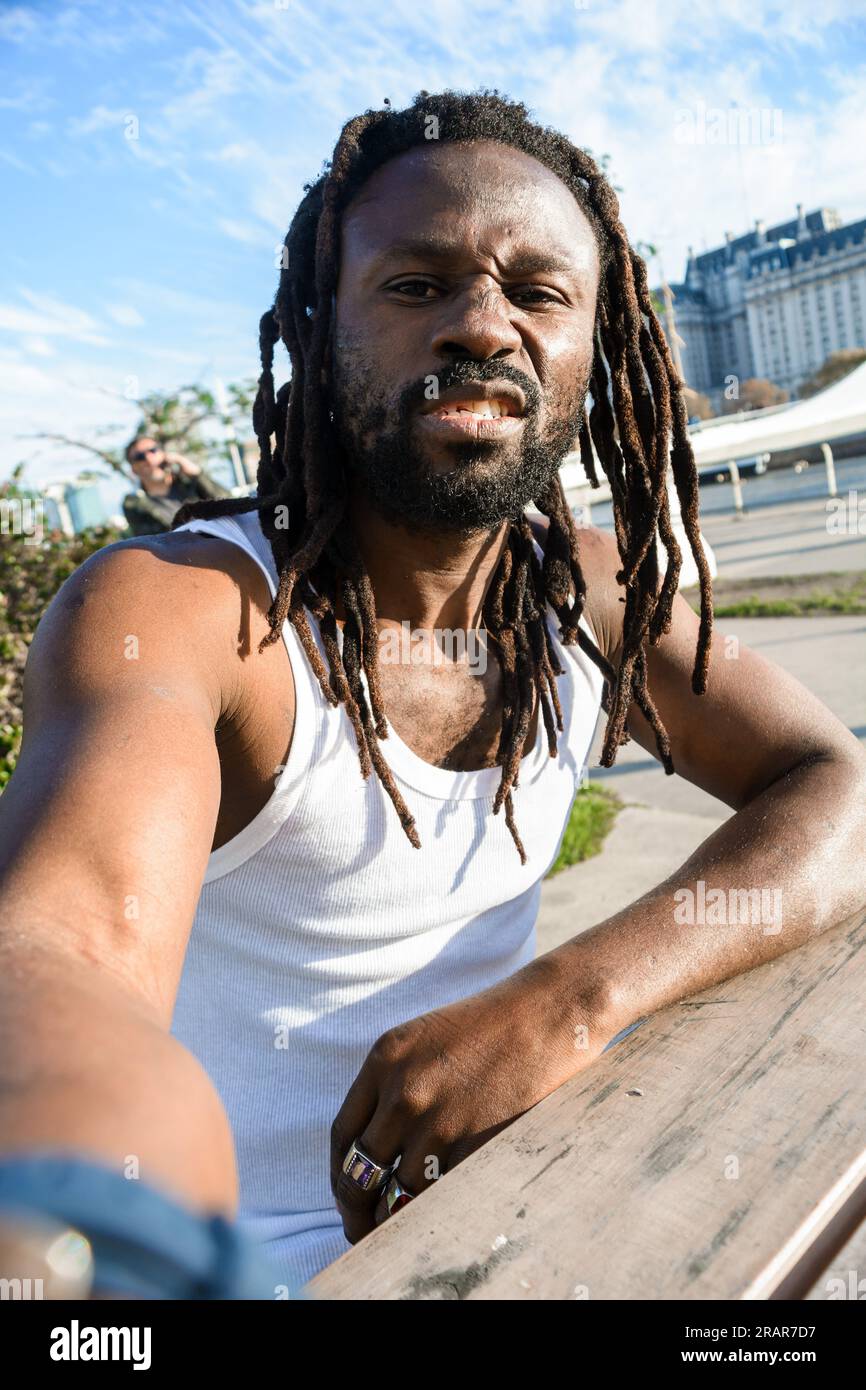 Vertical selfie portrait of young African man with dreadlocks and beard ...