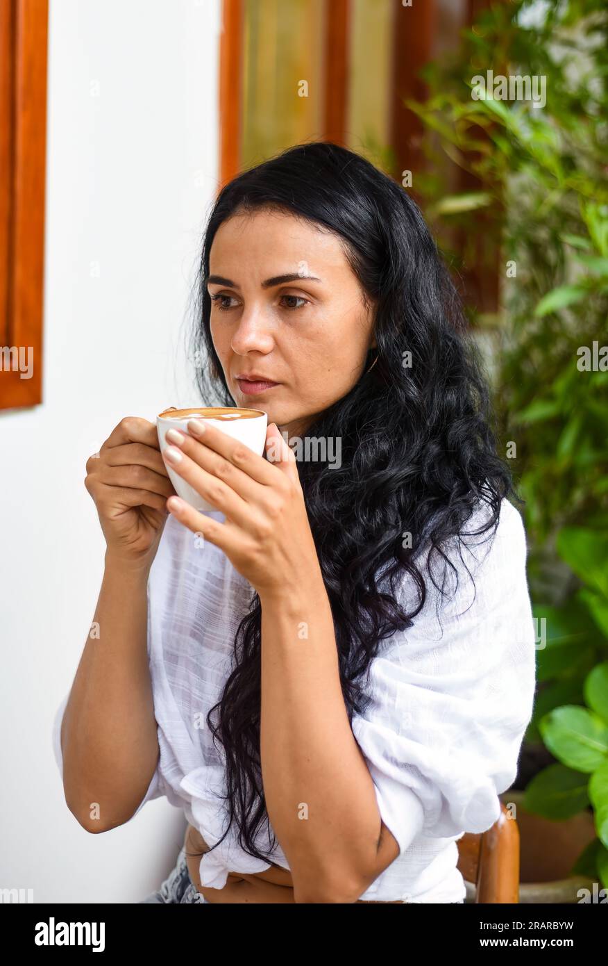 Portrait of smiling ukrainian woman drinking hot capuccino and looking ...