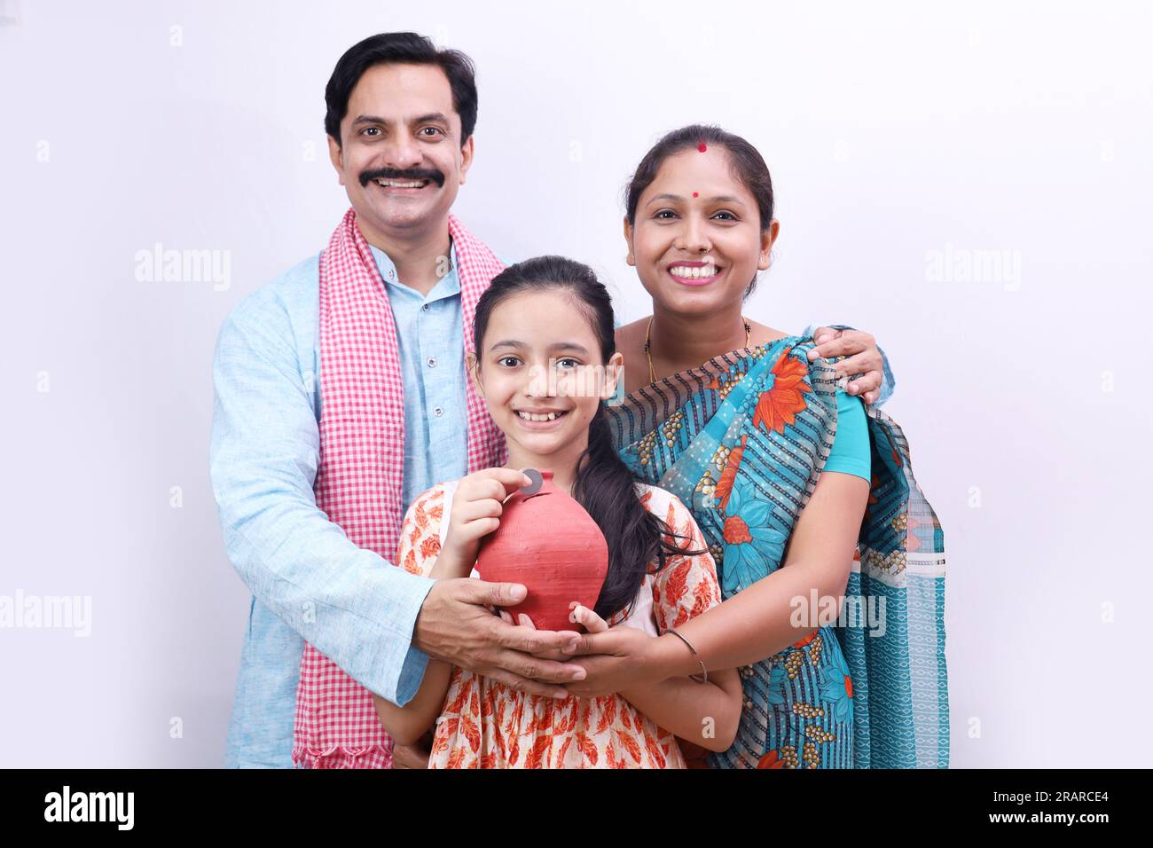 Happy Indian rural family in saree standing holding a piggy bank in ...