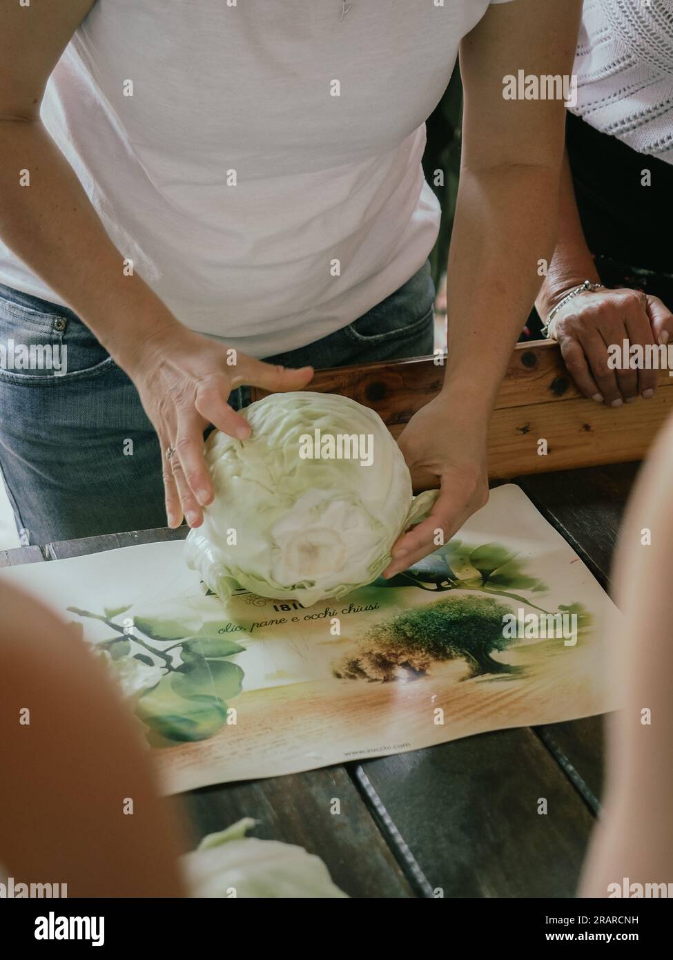woman cutting and kneading cabbage leaves to make a compress to lower ...