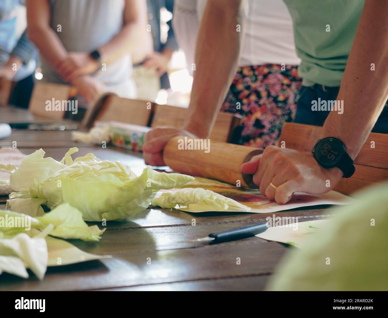 woman cutting and kneading cabbage leaves to make a compress to lower ...