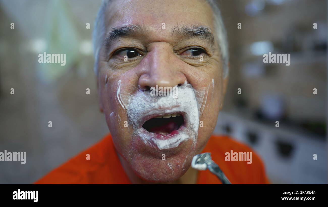 Older man shaving beard in front of bathroom mirror, old age domestic ...