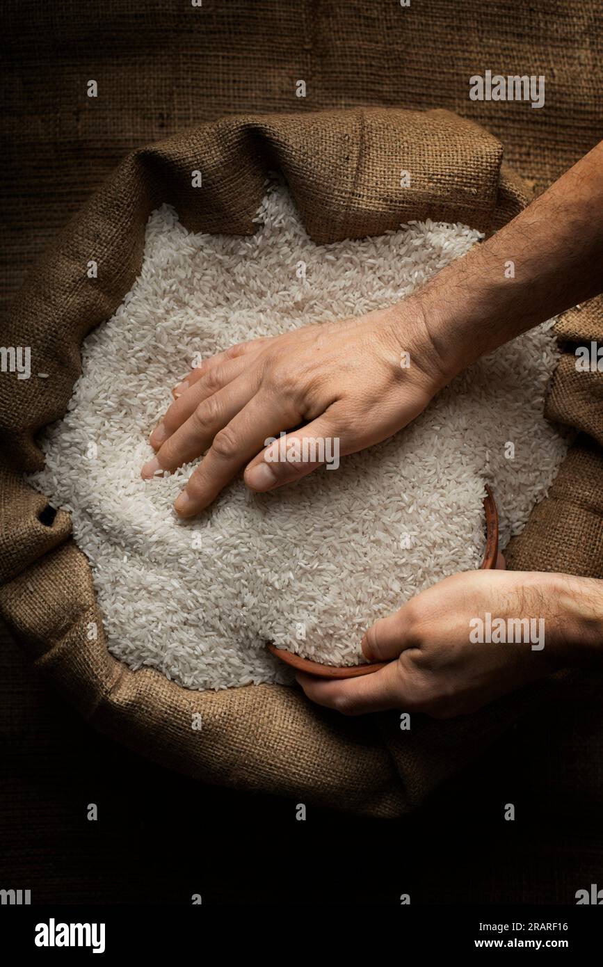 Human hands holding handful of rice over burlap sack Stock Photo - Alamy