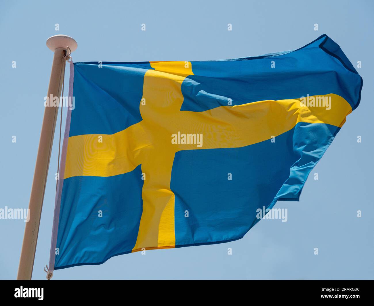 Sweden the Swedish flag waving in the wind on a flagpole with blue sky ...