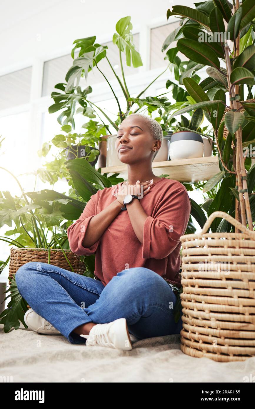 Wellness, peace and woman breathing by plants for meditation in a ...