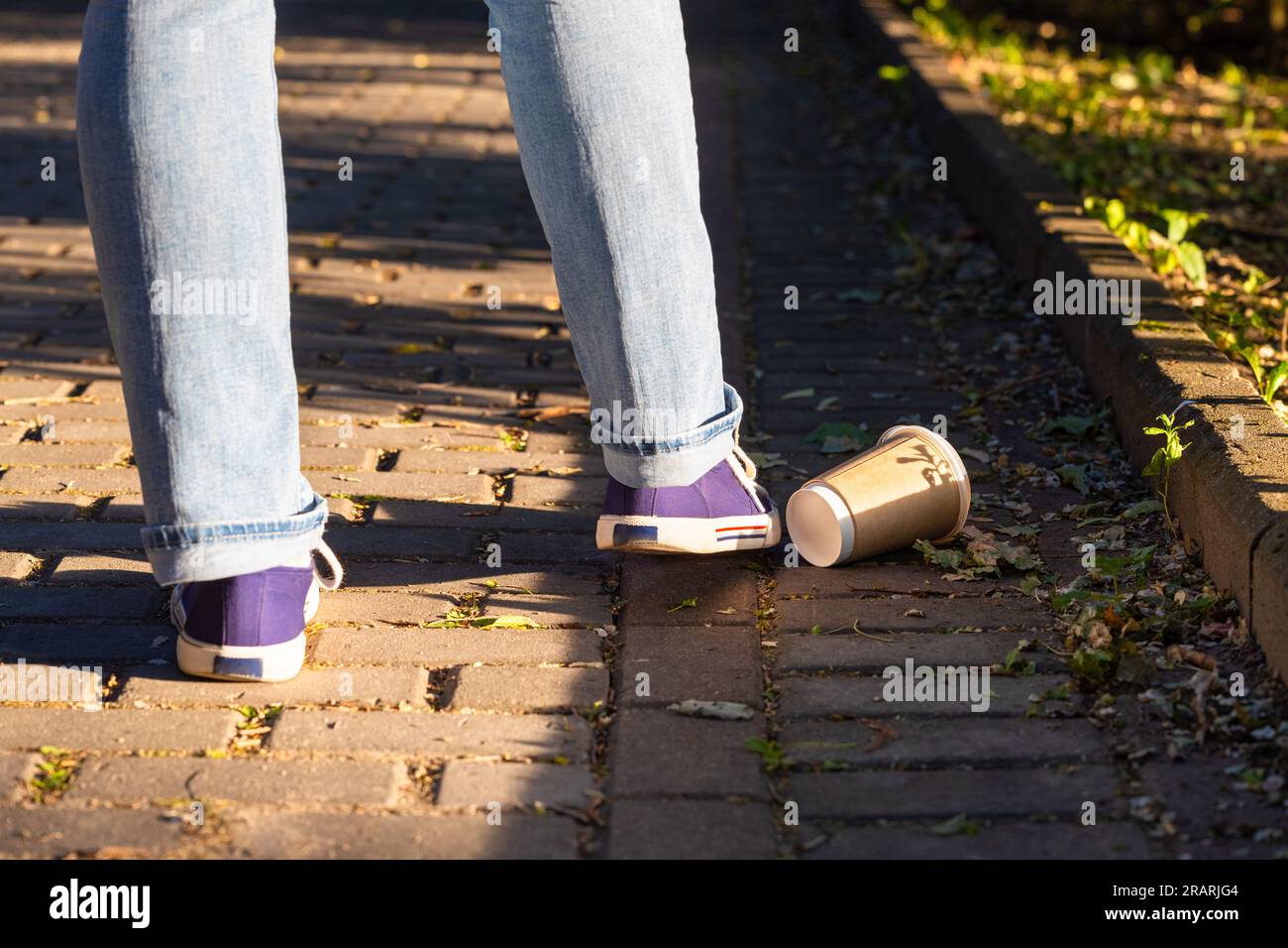 man kicking an empty paper coffee cup. man littering in the park ...