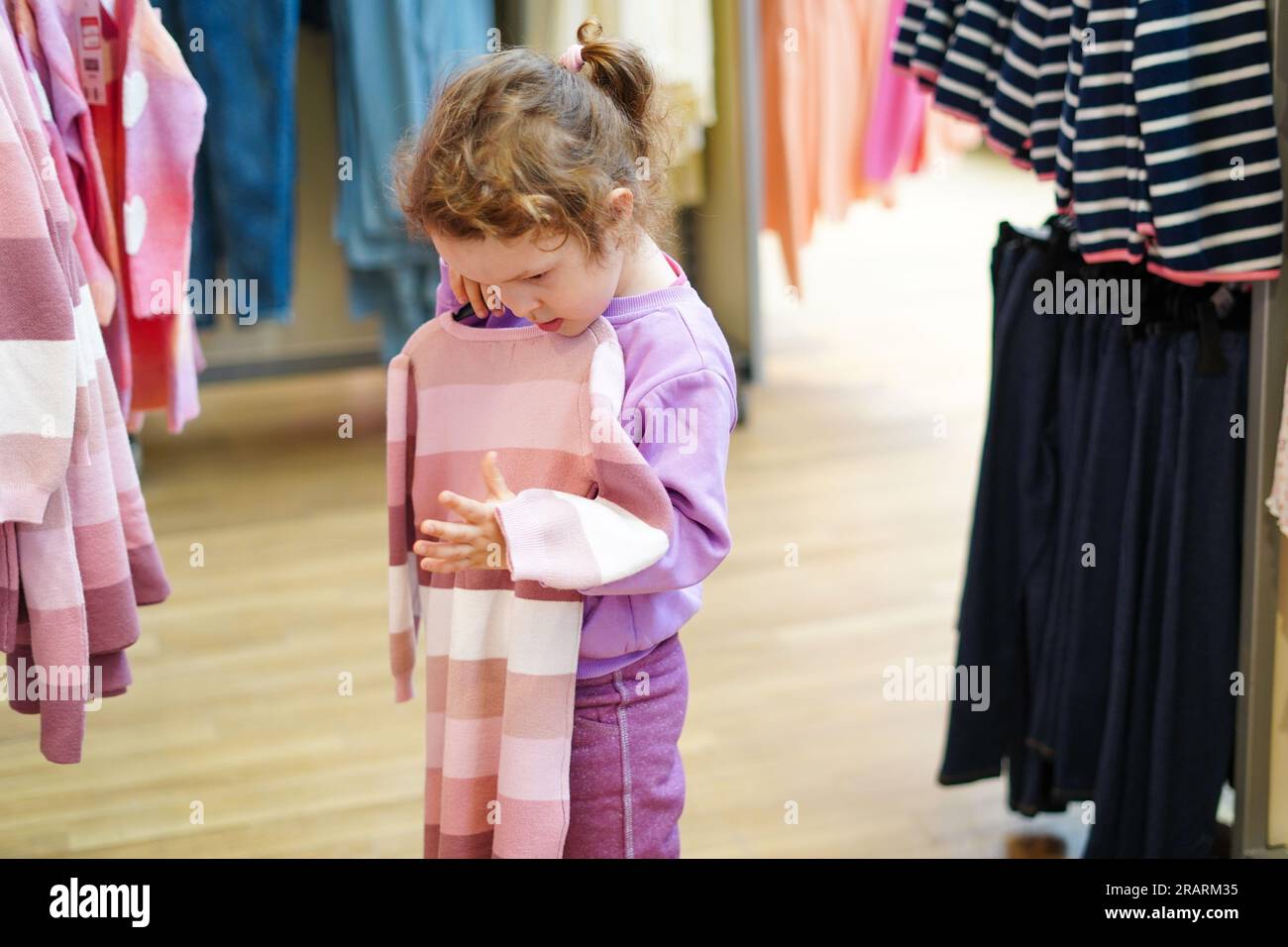 Cute child girl chooses dress in shop store with clothes Stock Photo ...
