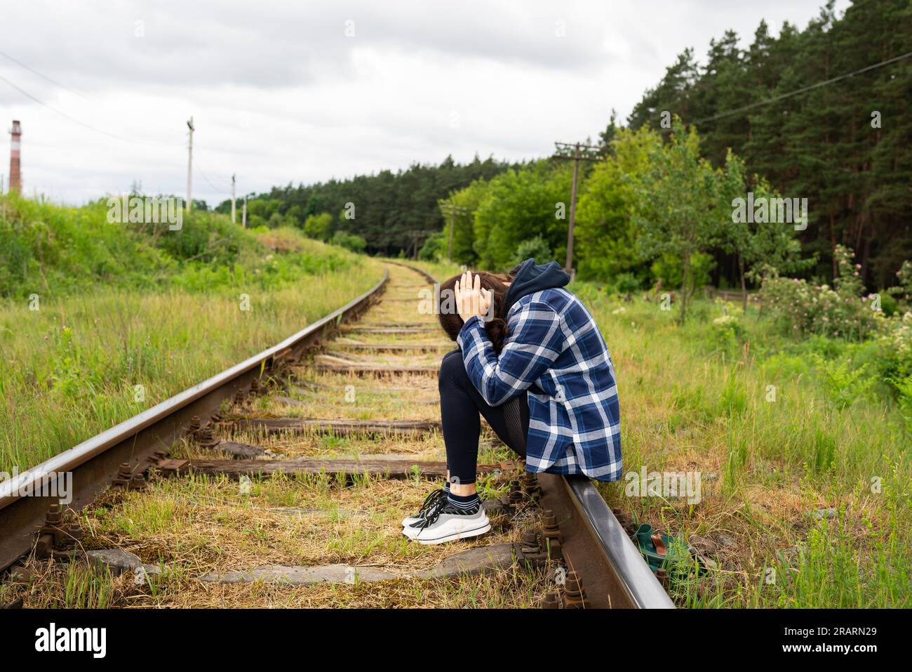 Stress, sadness, loneliness, pain. An upset girl sits on the rails, a ...