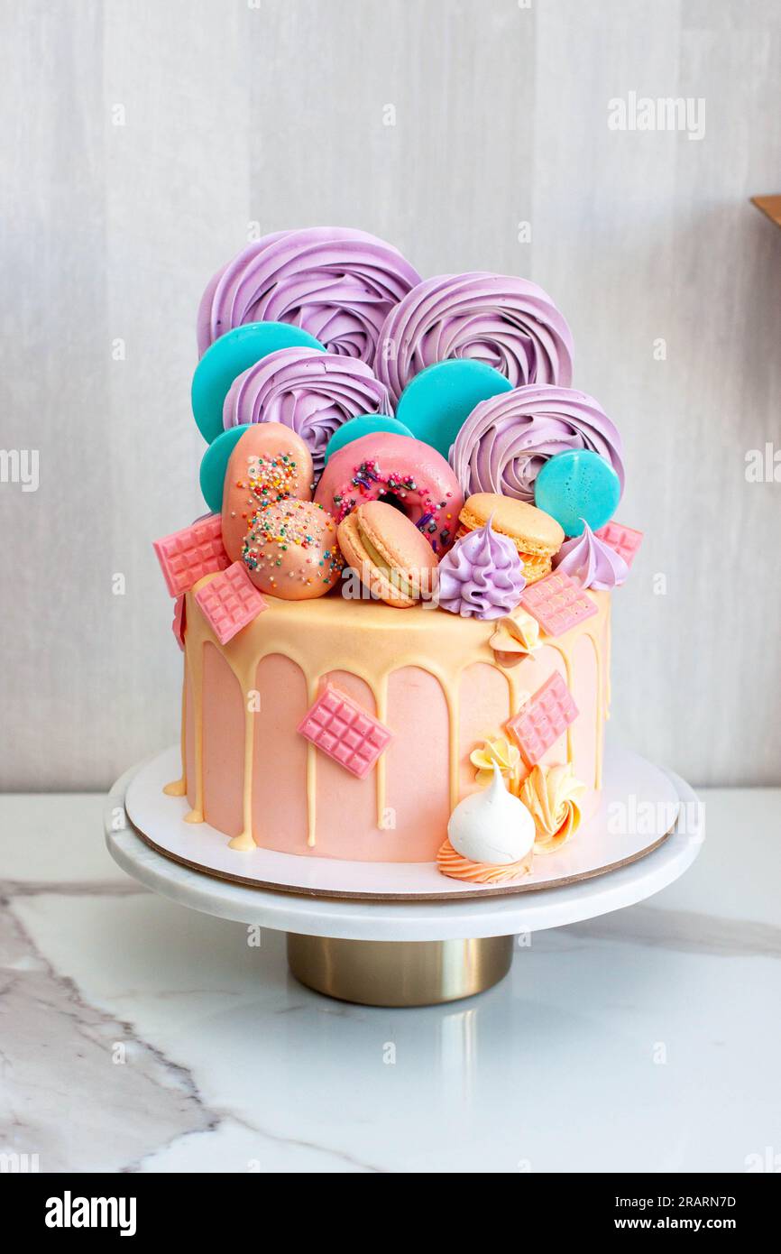 Pink cake decorated with colorful lollipops, donuts, popsicles ...
