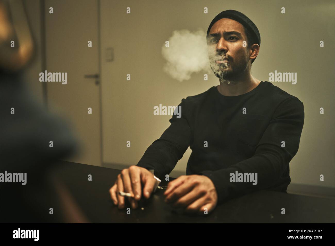 Man in handcuffs, smoking and talking to detective in interrogation ...