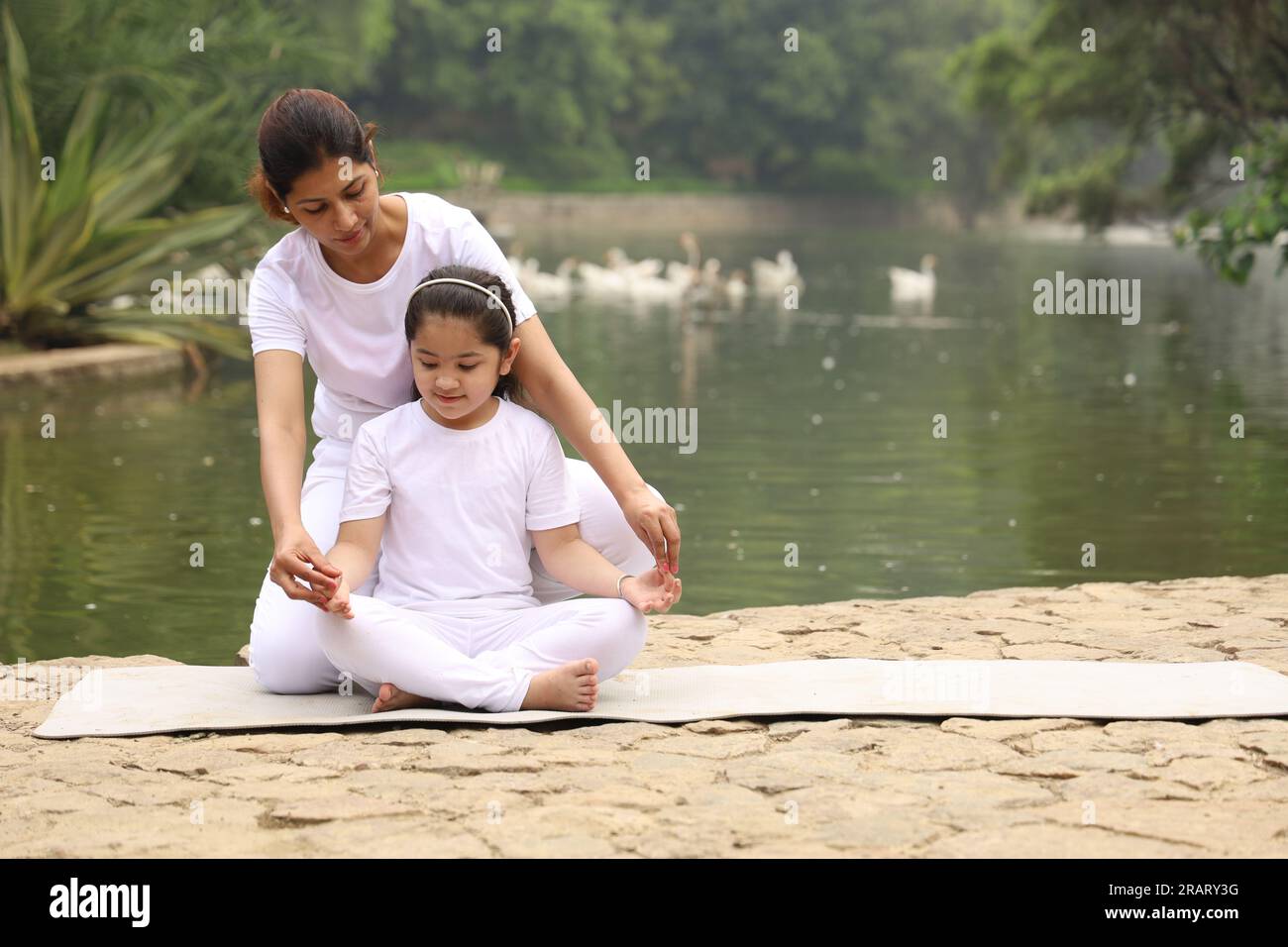 Healthy mom teaching Yoga poses in green serene environment early ...