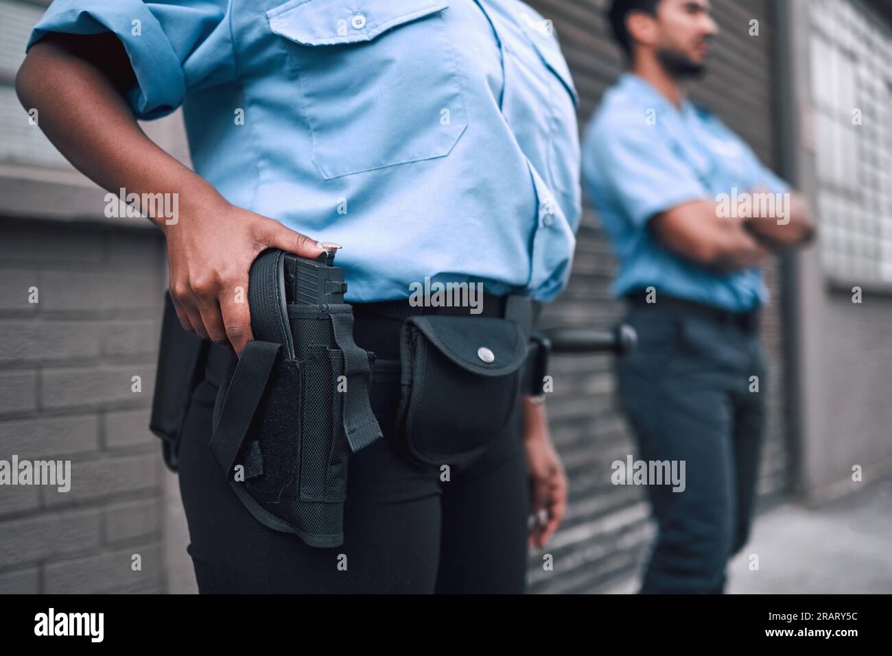 Hand, gun and security with a police officer on duty or patrol in the ...