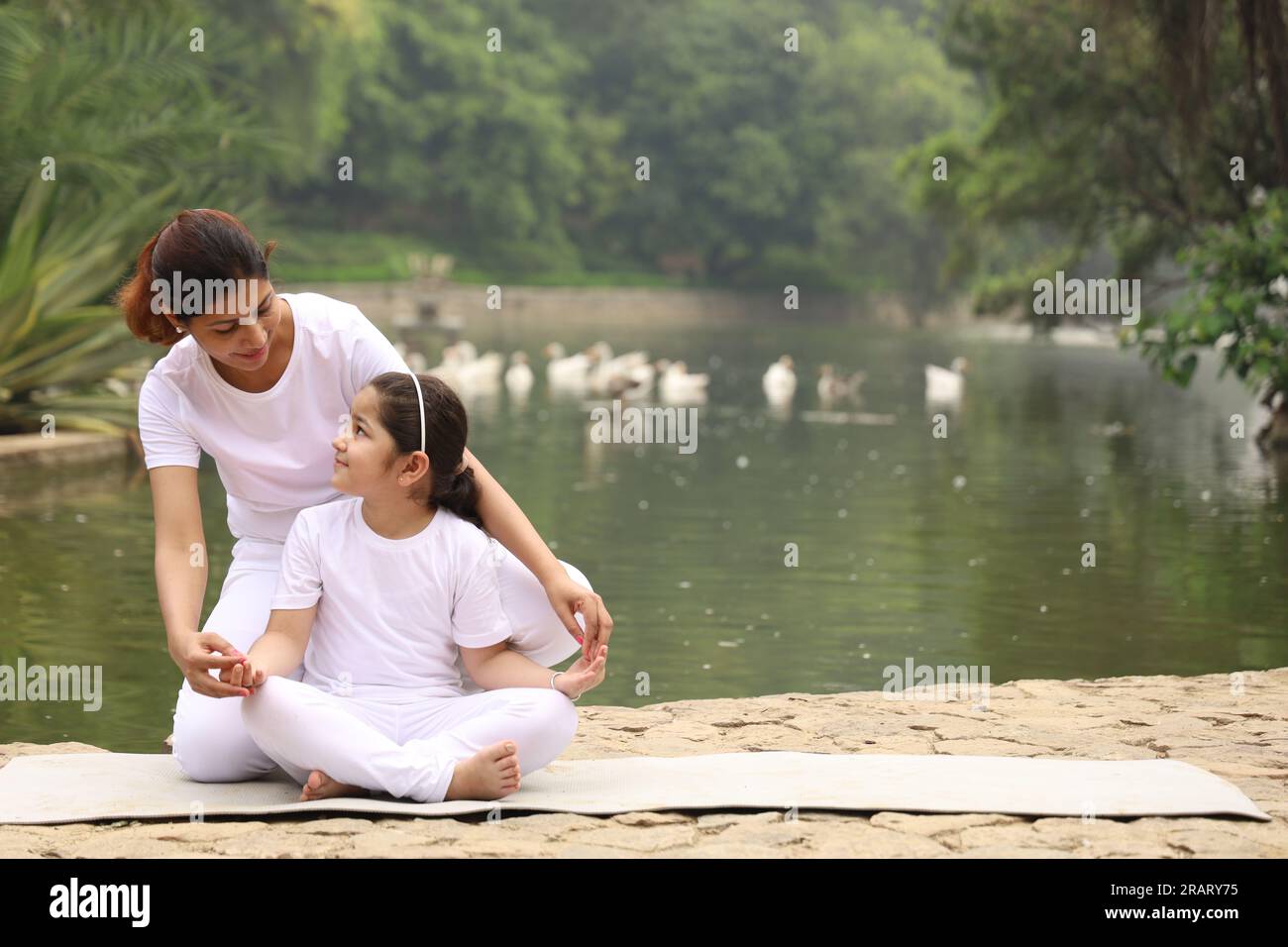Healthy mom teaching Yoga poses in green serene environment early ...