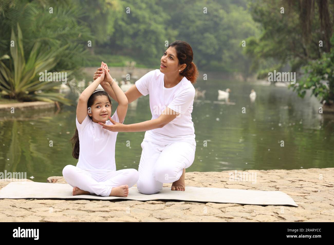 Healthy mom teaching Yoga poses in green serene environment early ...