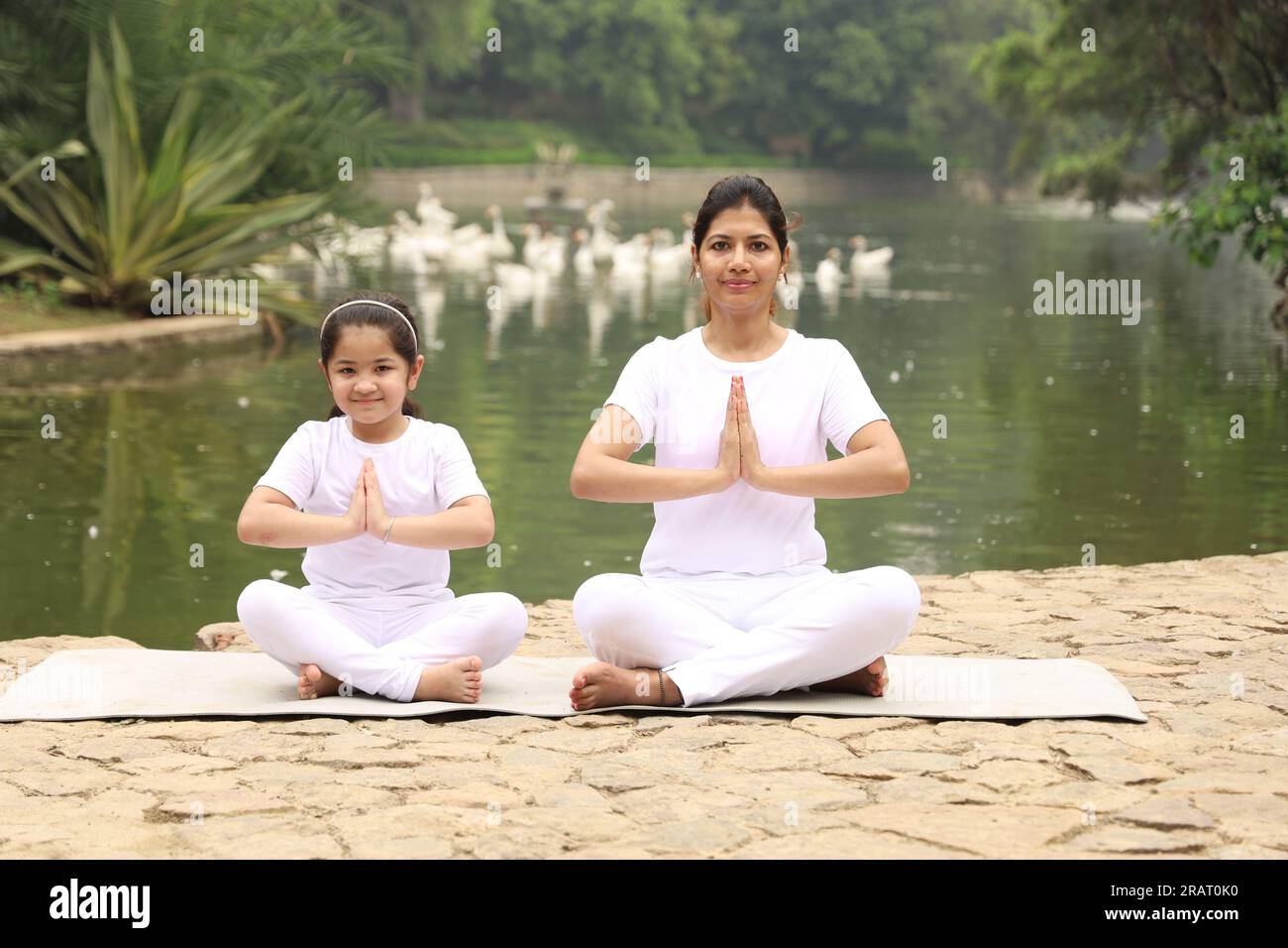 Healthy mom teaching Yoga poses in green serene environment early ...