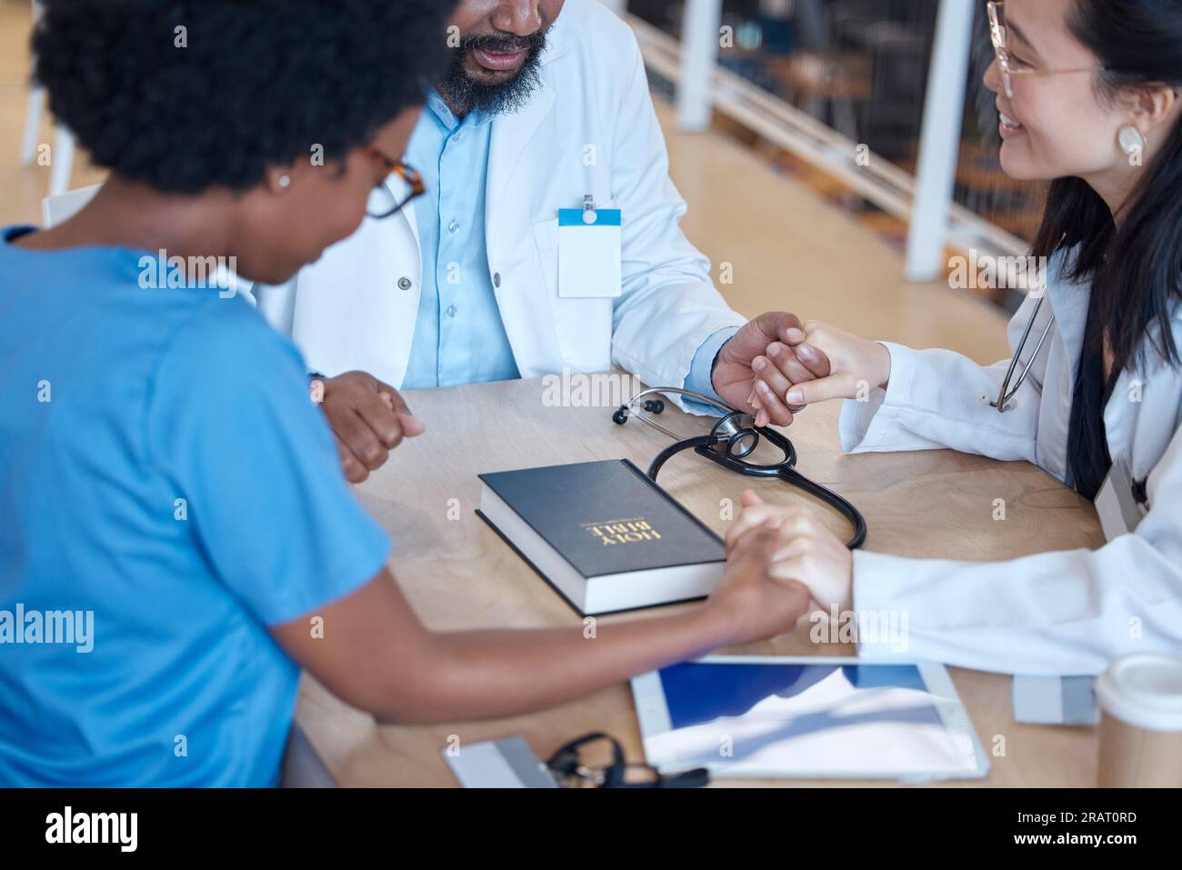 Hands, bible and a medical team praying during a meeting in a hospital ...