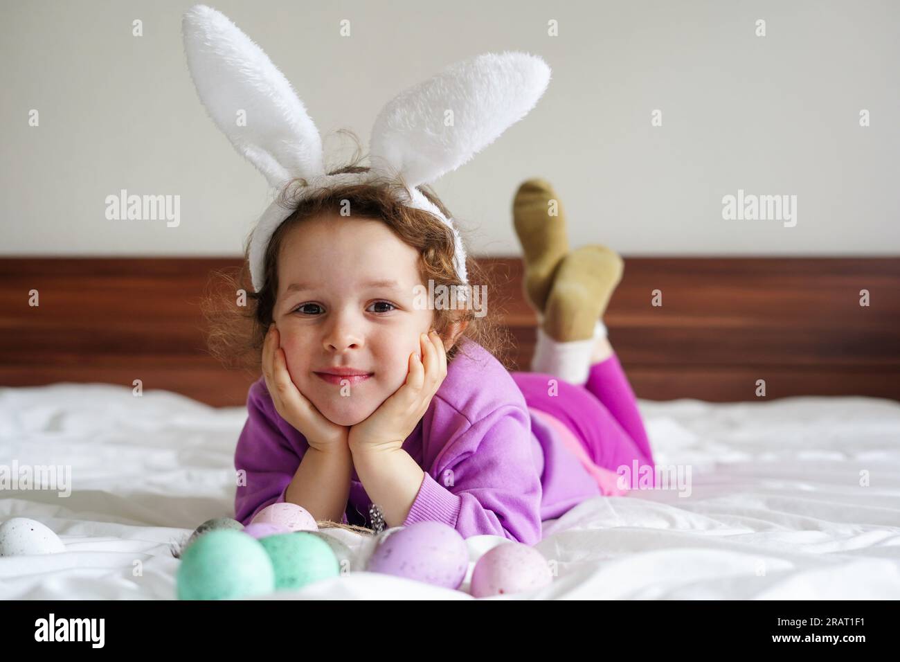 Happy Easter. cute beautiful girl with curly hair and bunny ears laying ...